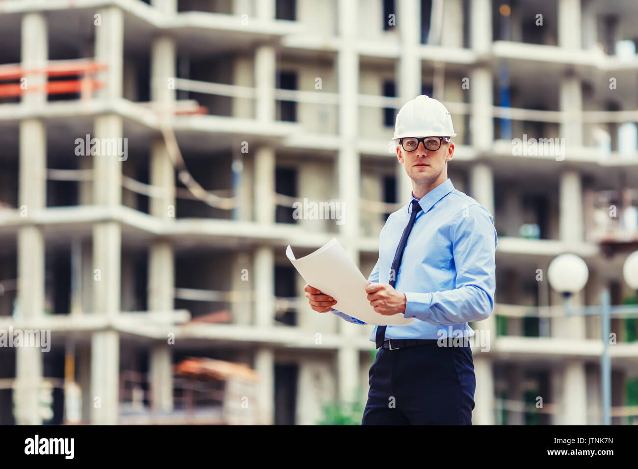 Handsom construction engineer at the construction site looking at the ...