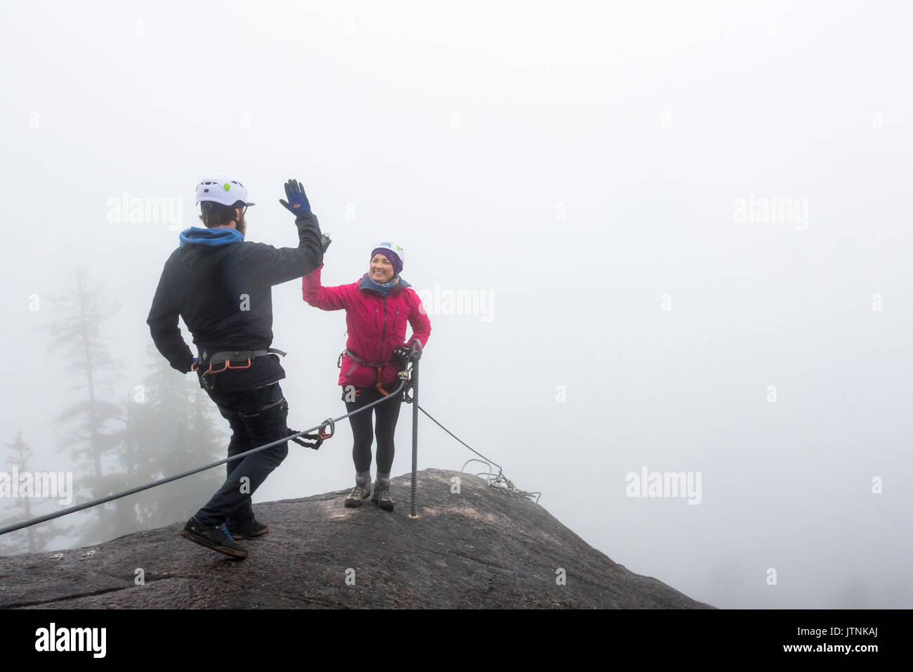 A man and a women slap a hi-five while doing the Via Ferrata on a rainy ...