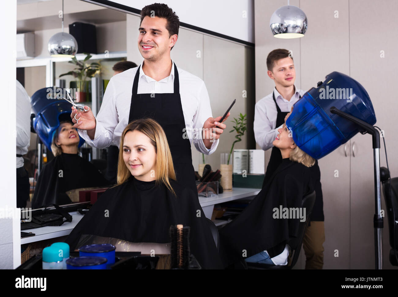 Professional hairstylist cuts hair of blonde girl at the beauty salon ...