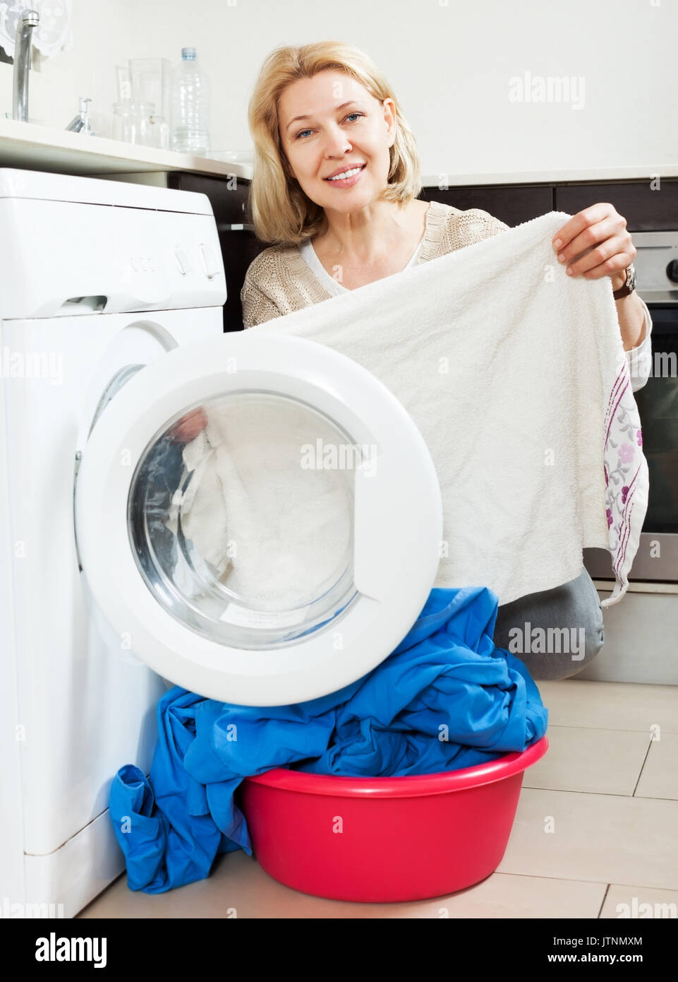 Smiling mature woman using washing machine at home laundry Stock Photo ...