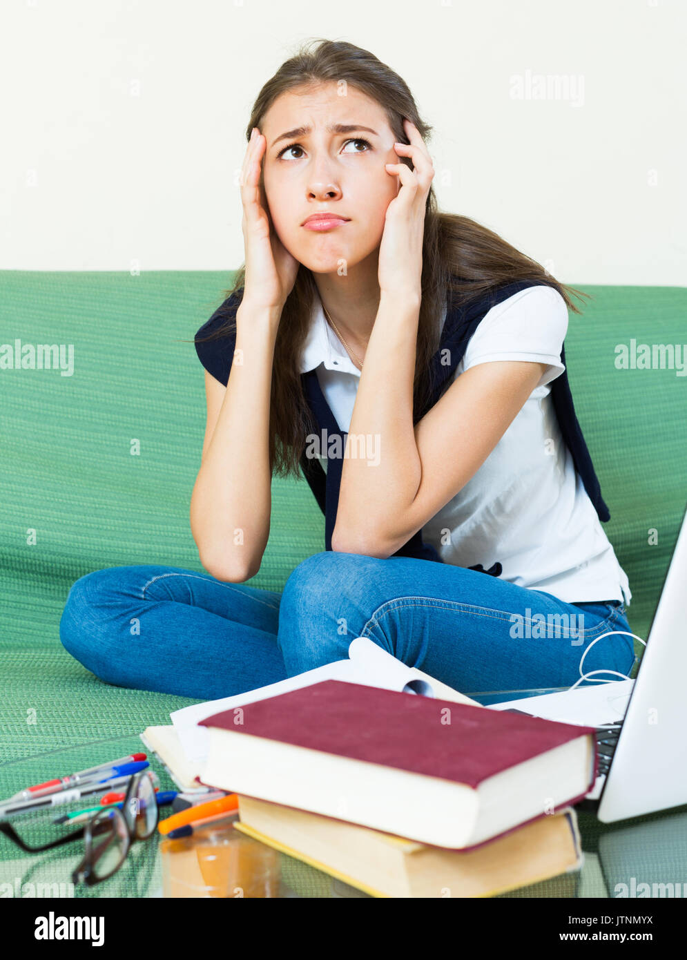 Nervous teenager doing homework on the couch at home Stock Photo - Alamy