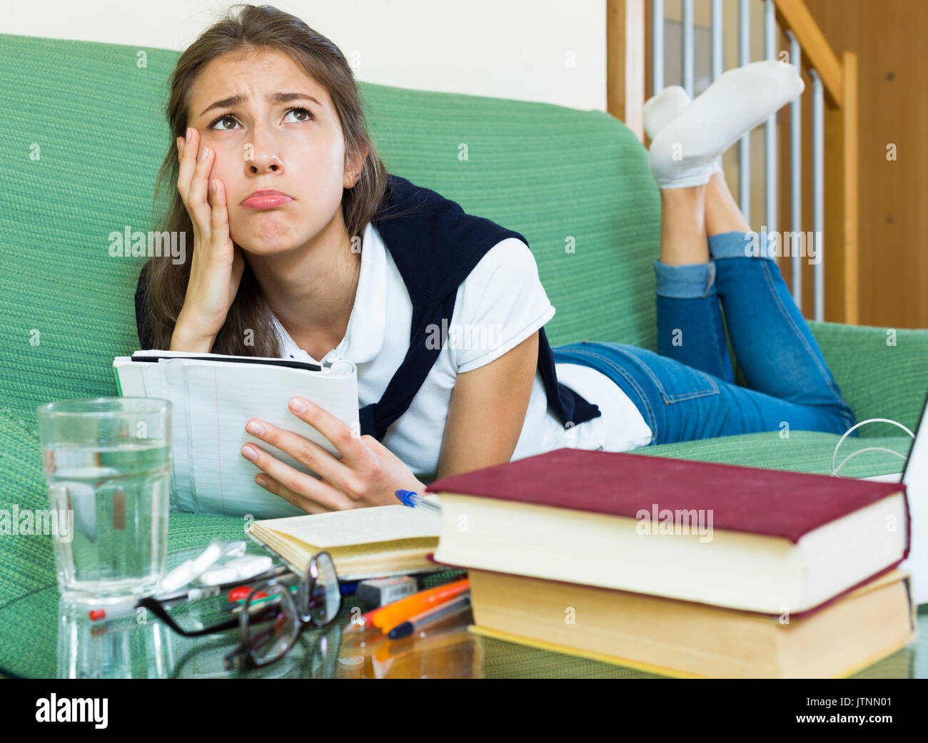 Nervous teenager doing homework on couch in the home Stock Photo - Alamy