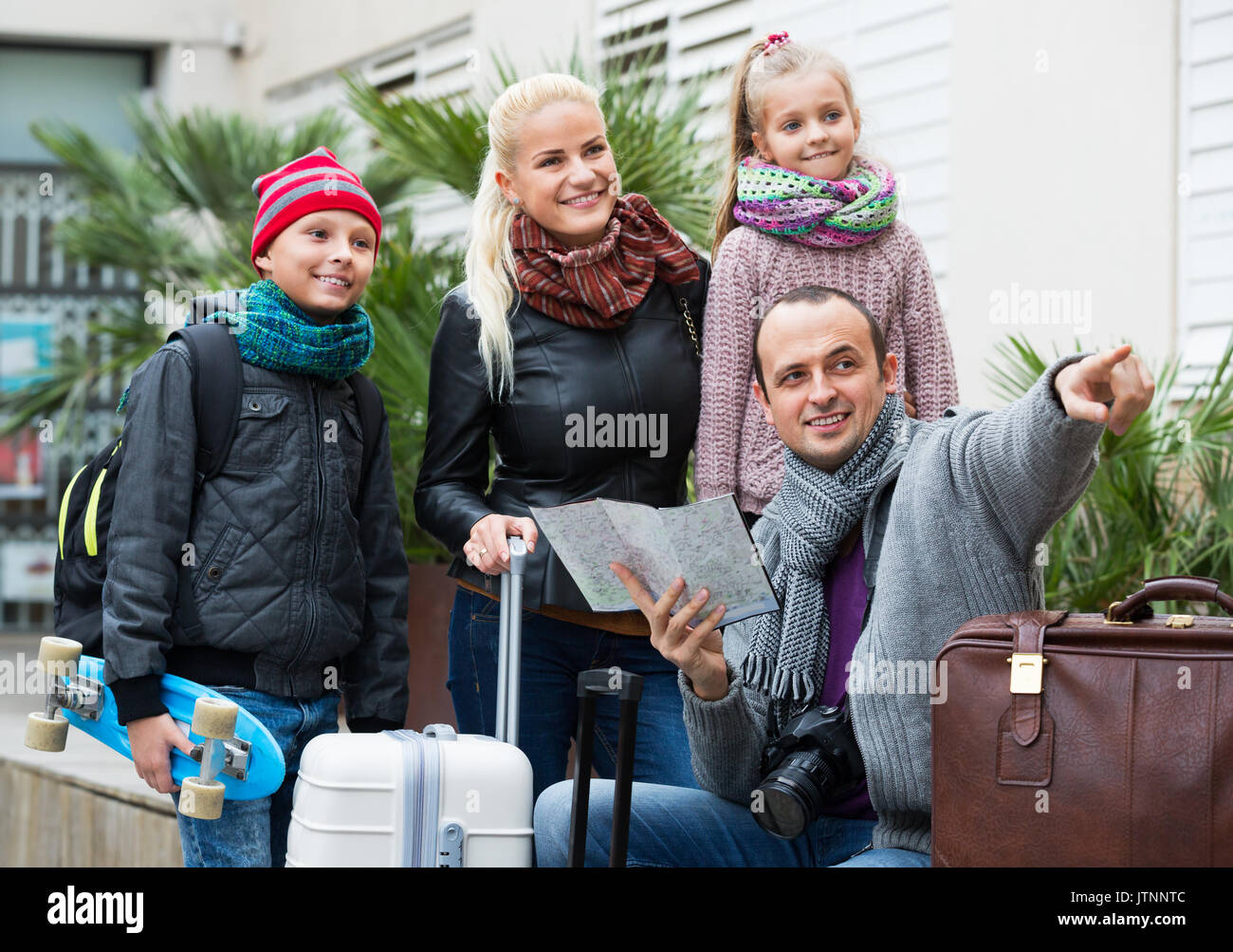 Happy middle class family of four checking a direction in a map outdoor ...