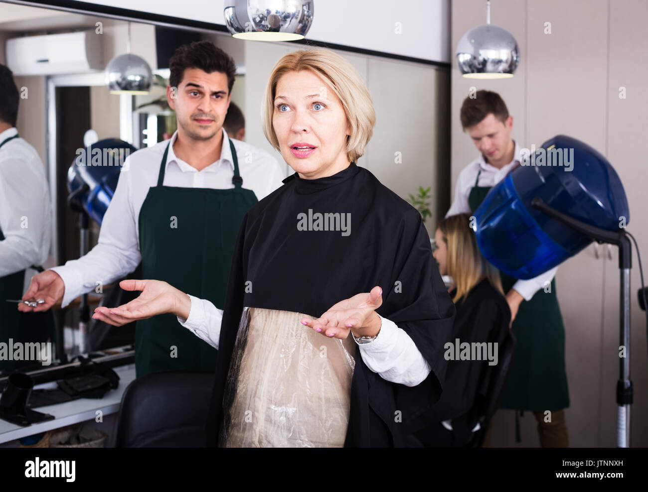 Furious senior woman screaming on hairstylist as hair cut badly Stock ...