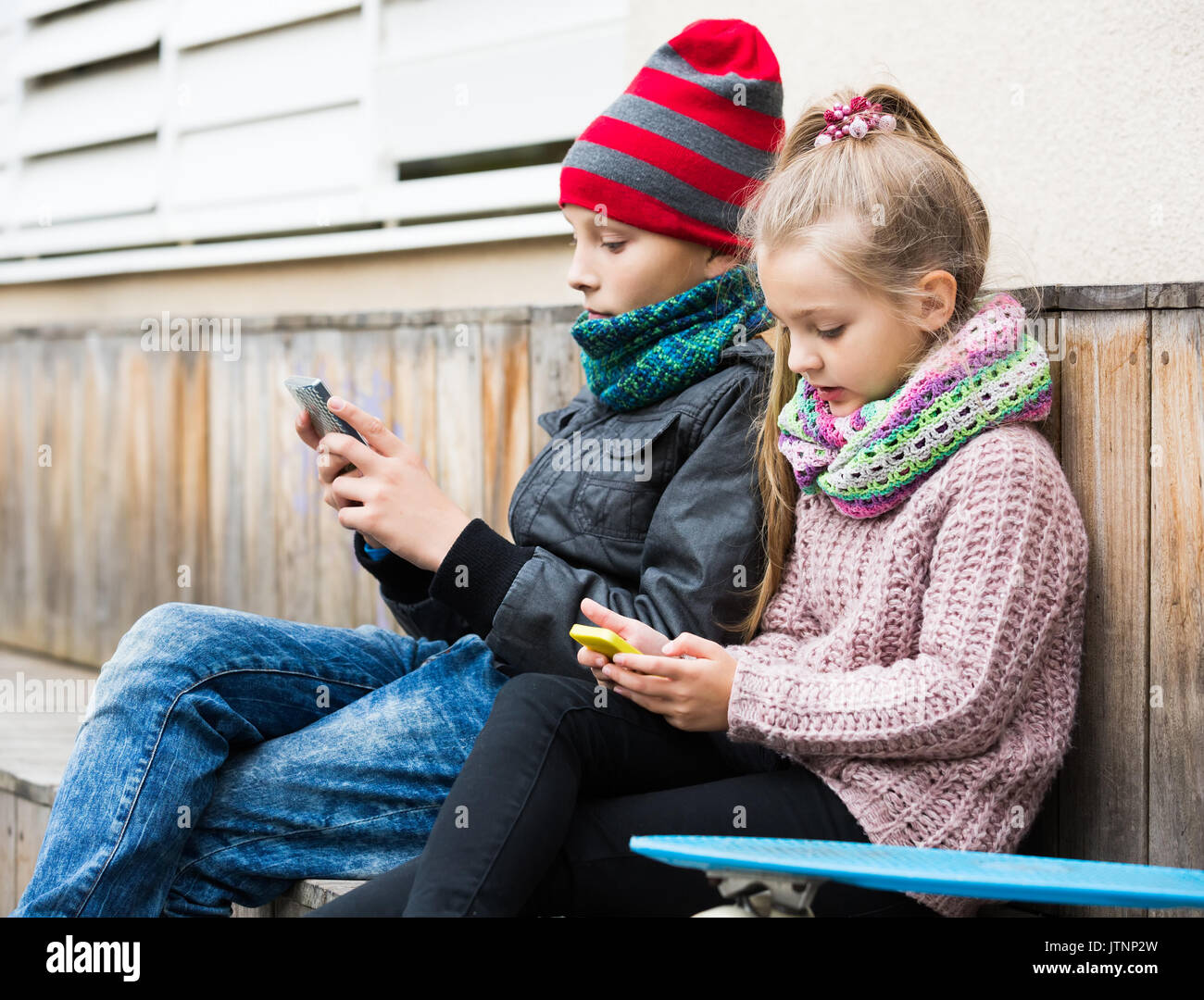 Positive spanish siblings playing with phones on autumn street Stock ...