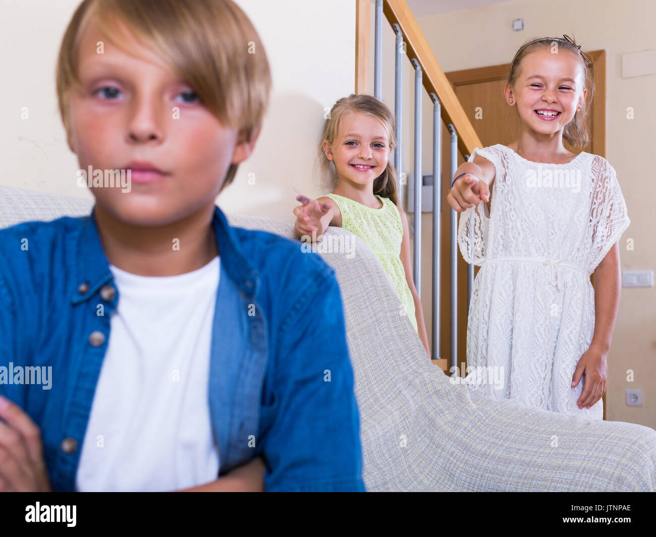 Two little girls talking and sulky boy sitting separately at home ...