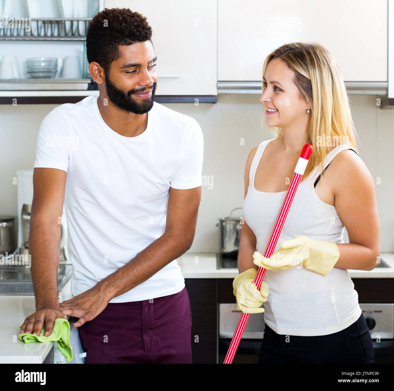 Black man with cheerful white woman dusting in domestic kitchen Stock ...