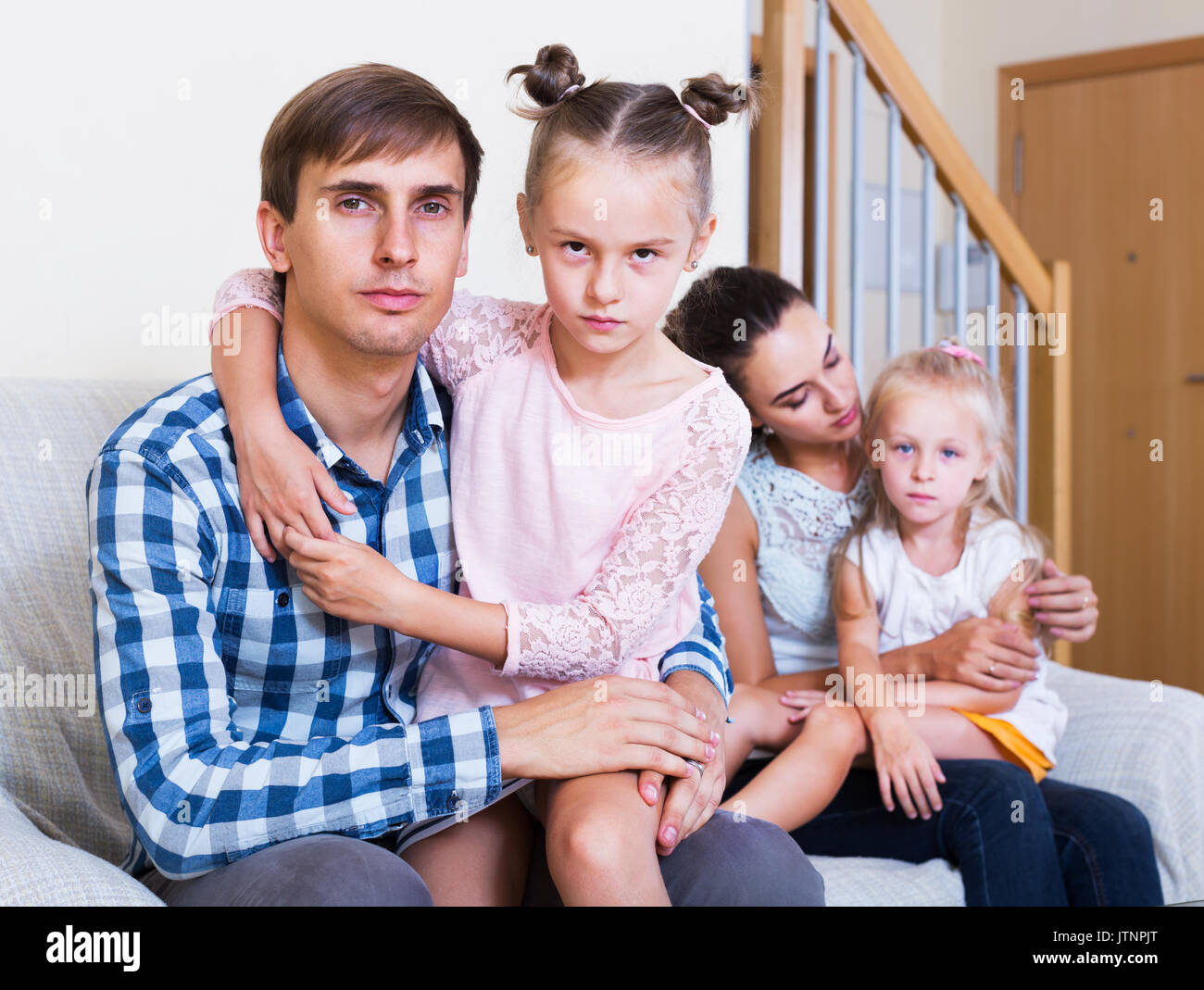 Portrait of sad family of four discussing separation indoors Stock ...