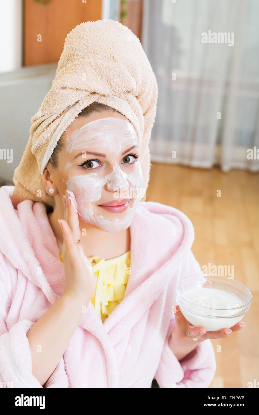 Portrait of young girl lying on couch with cream over face indoors ...