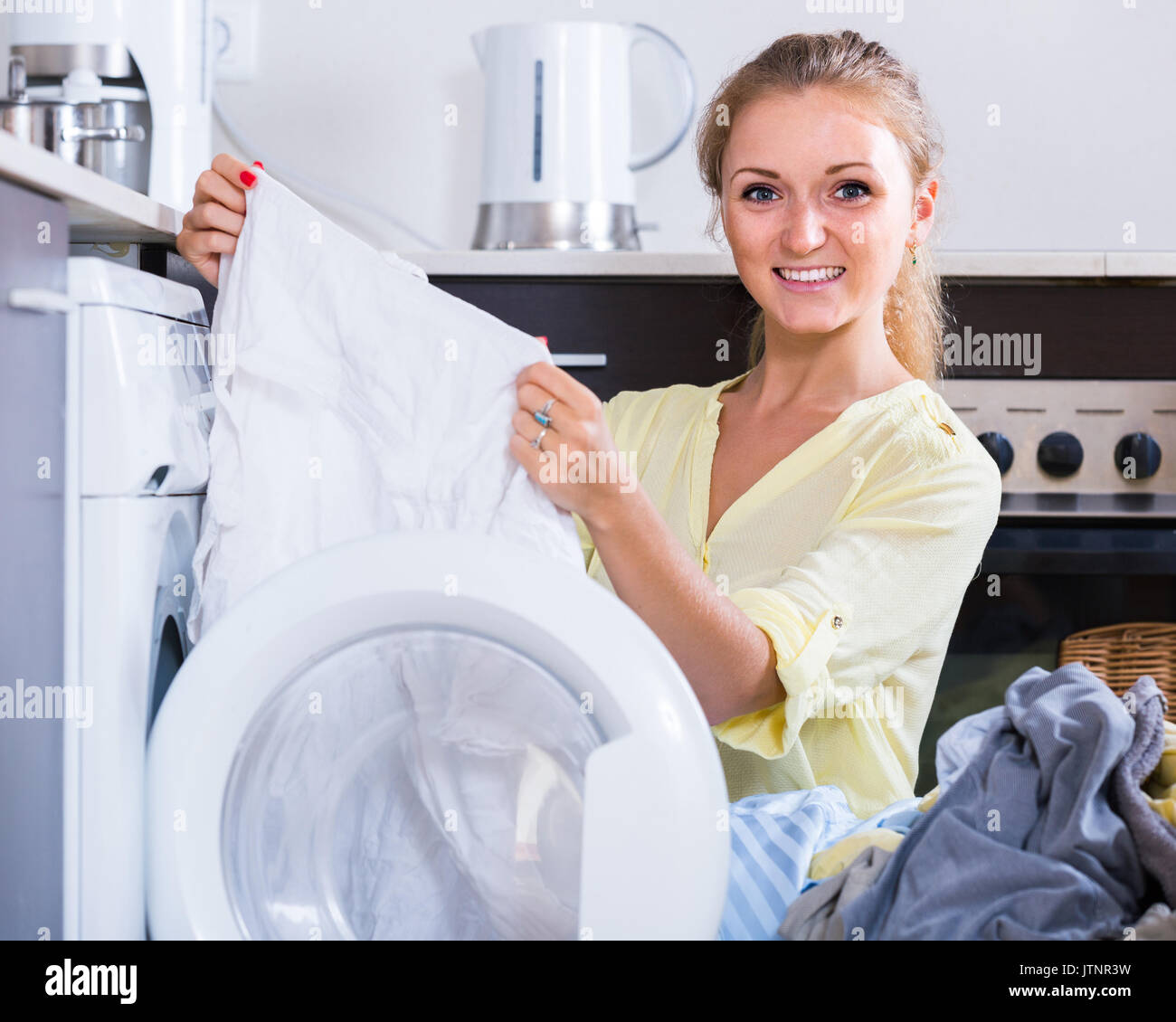 Portrait of smiling american housewife taking clothes out washing ...