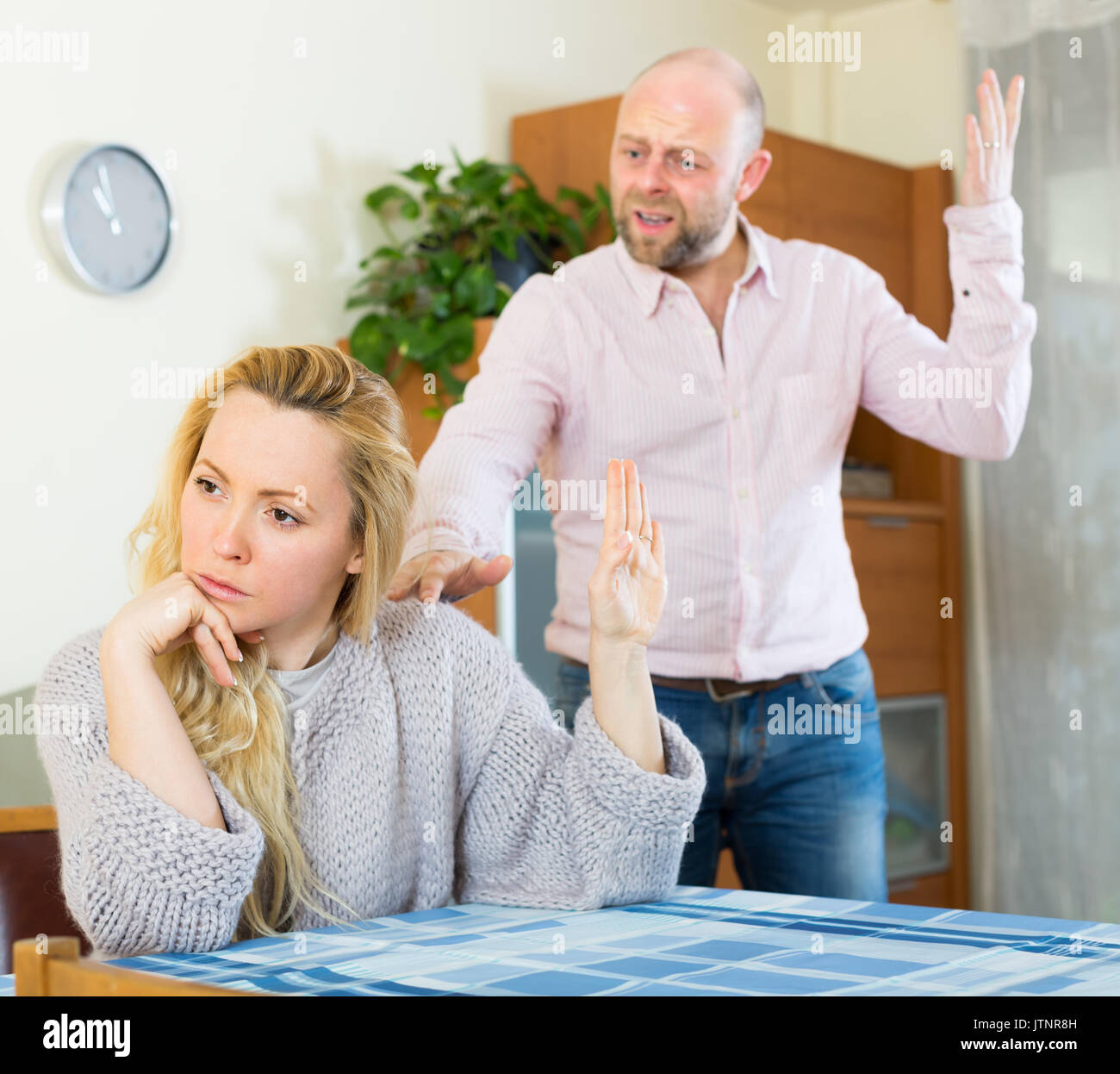 Angry man and sad young woman having quarrel in the living room at home ...