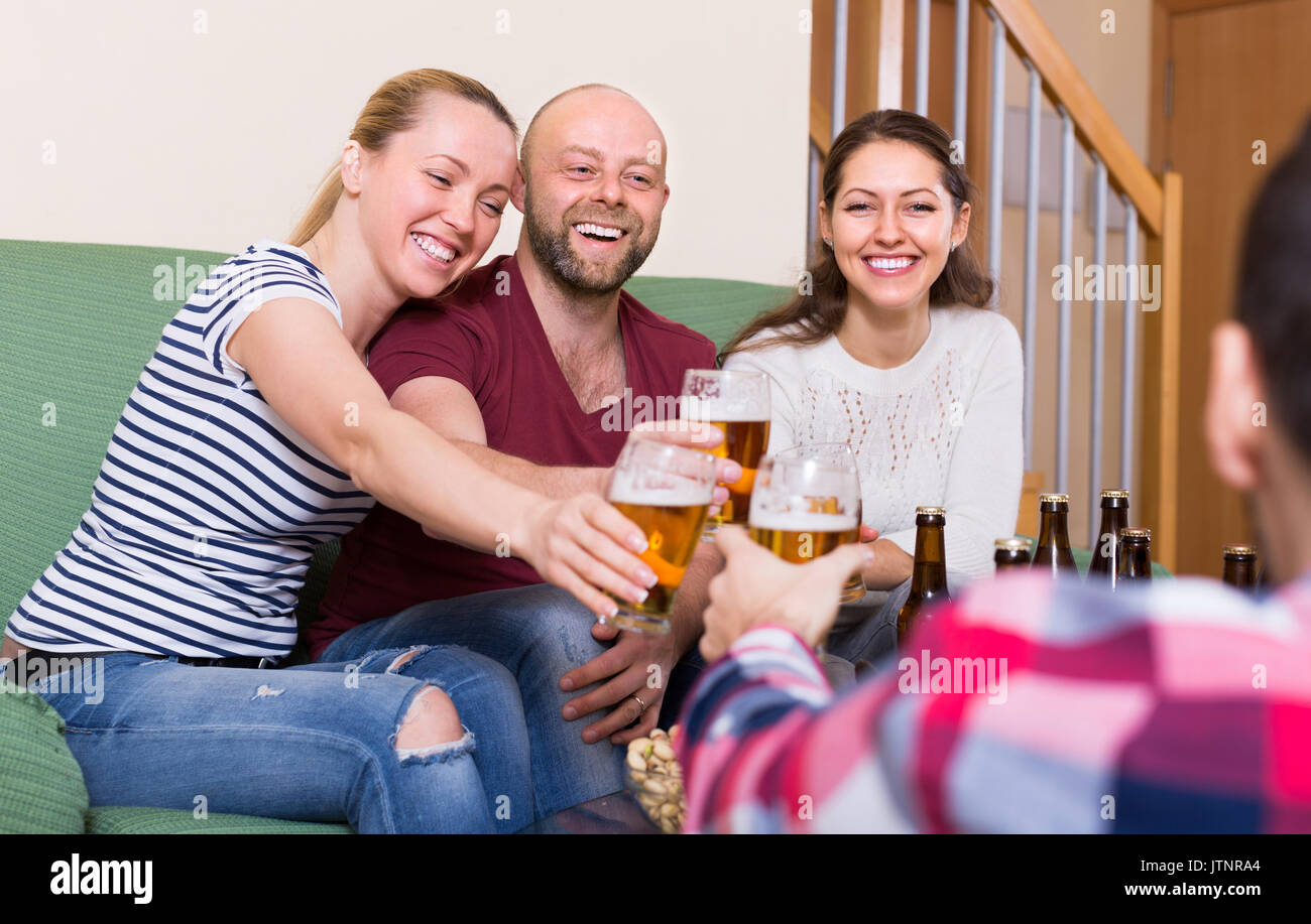 Cheerful laughing young adults drinking beer at home Stock Photo - Alamy