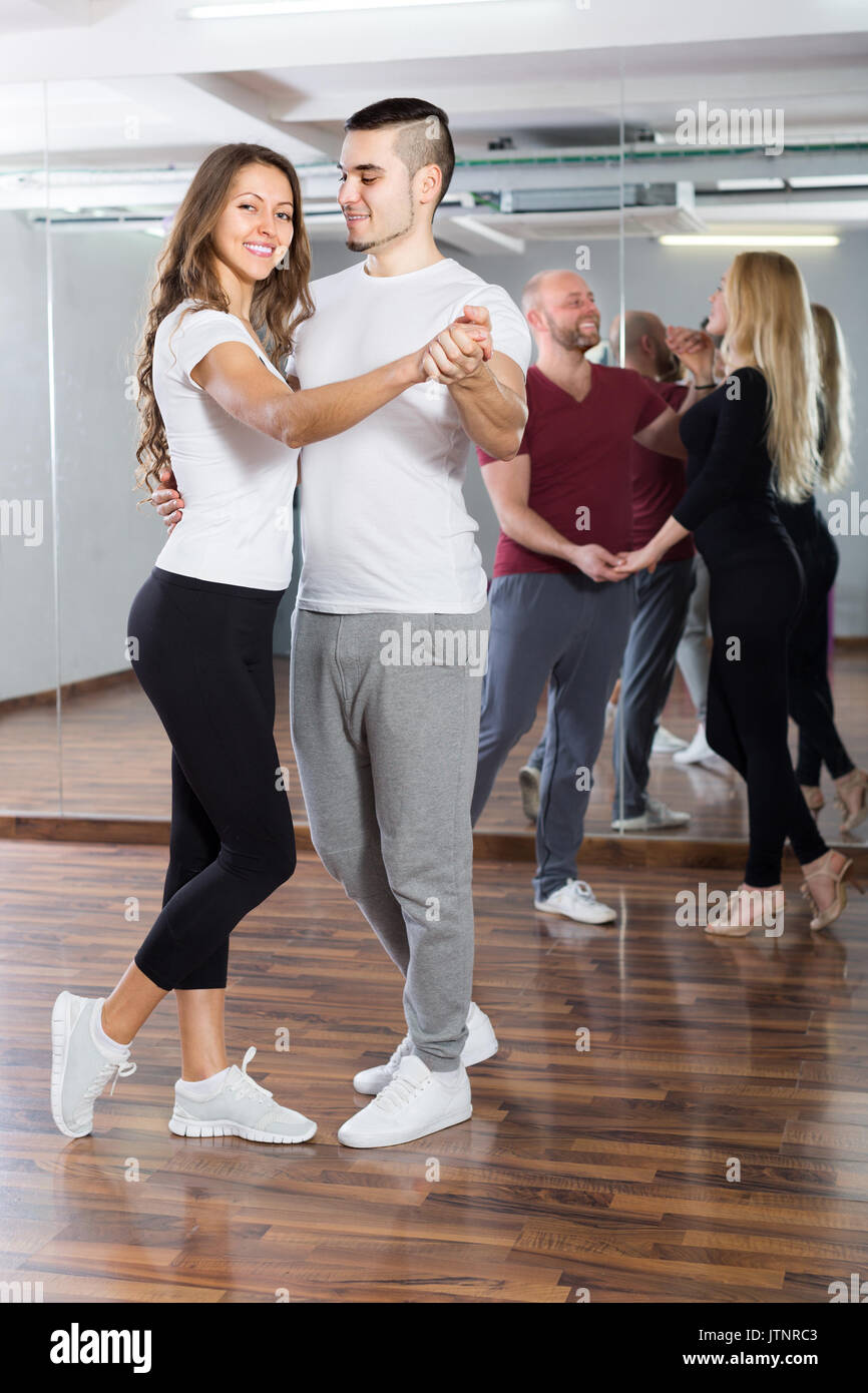 Group of cheerful smiling young adults dancing salsa at dance class ...