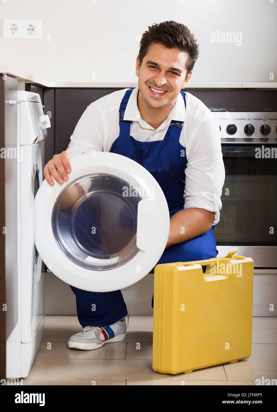Professional mechanic repairing washing machine in domestic interior ...
