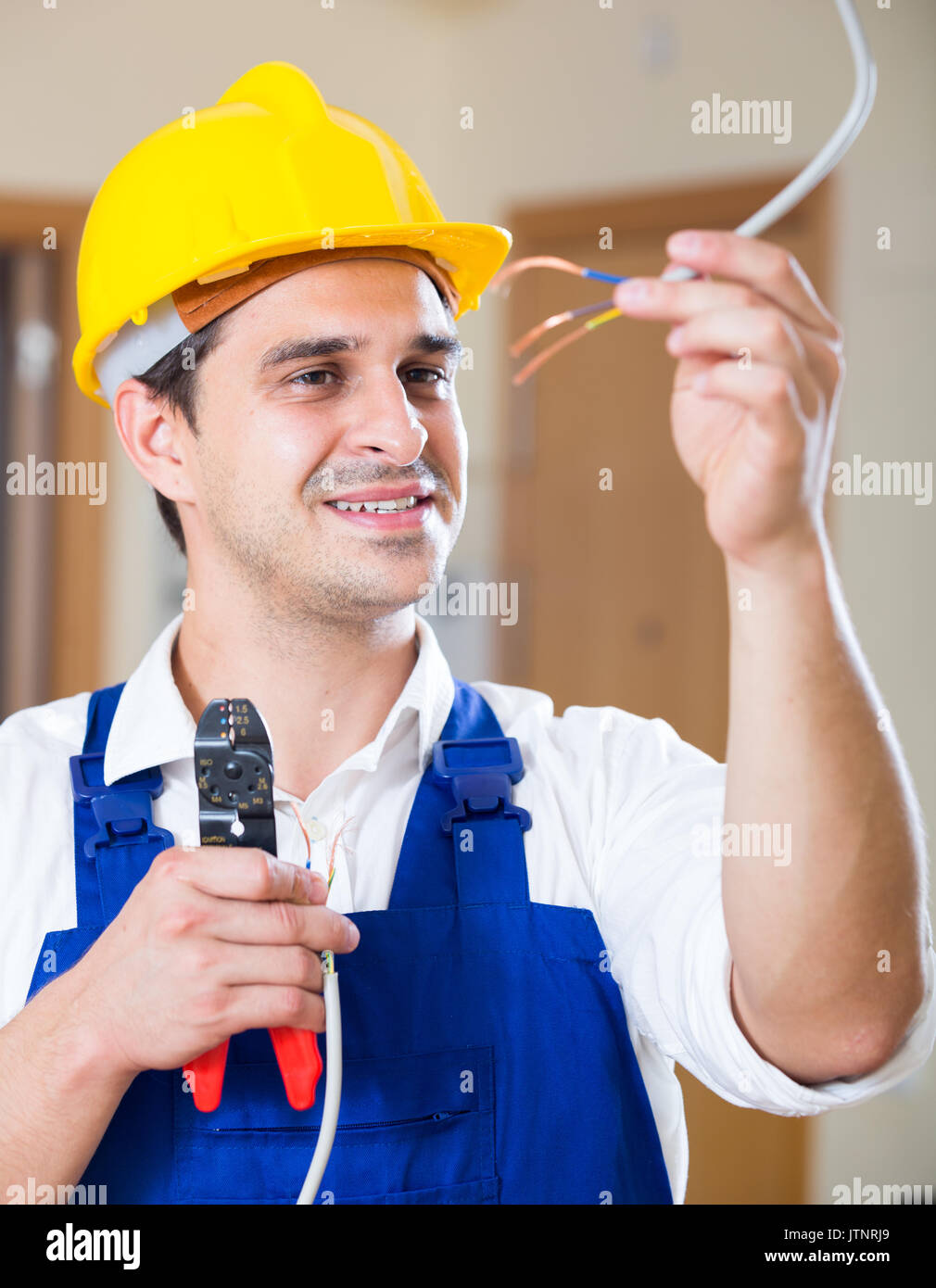 Professional electrician working with wires at client home Stock Photo ...