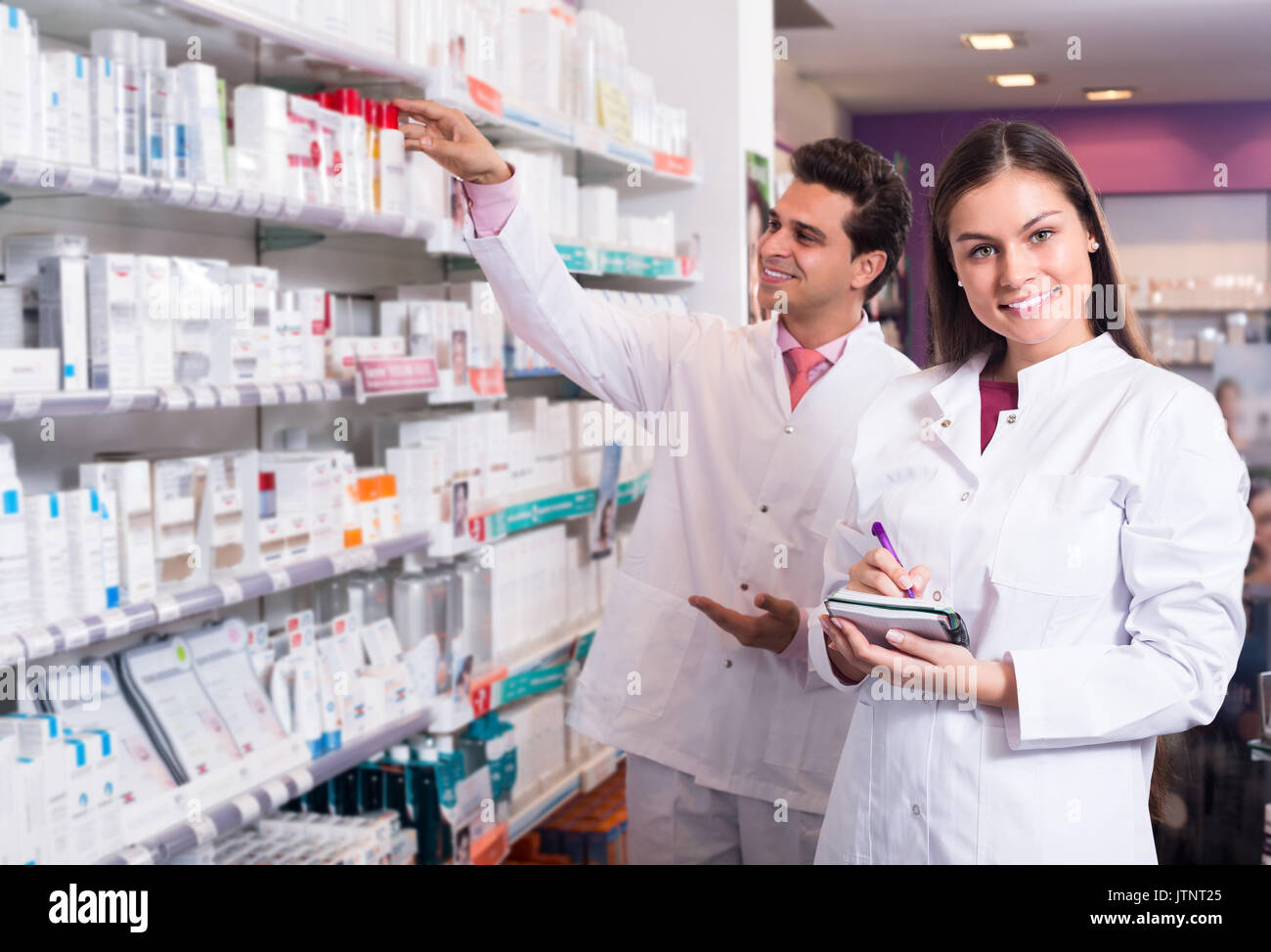 Portrait of two friendly smiling pharmacists in uniform working in ...