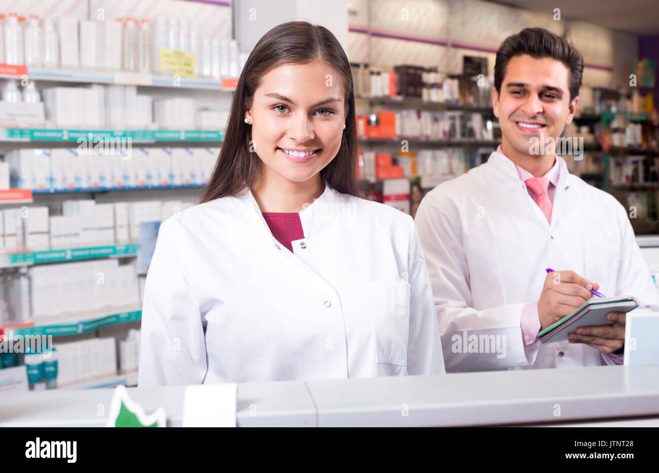 Portrait of two smiling pharmacists in uniform working in modern ...