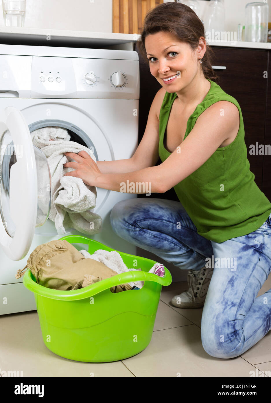 Home laundry. Cheerful smiling girl using washing machine at home Stock ...