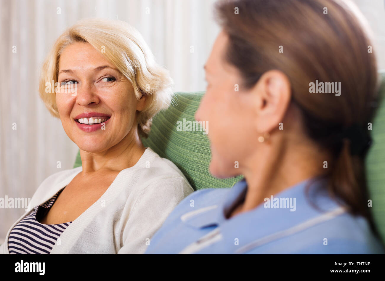 two happy mature women talking at home Stock Photo - Alamy