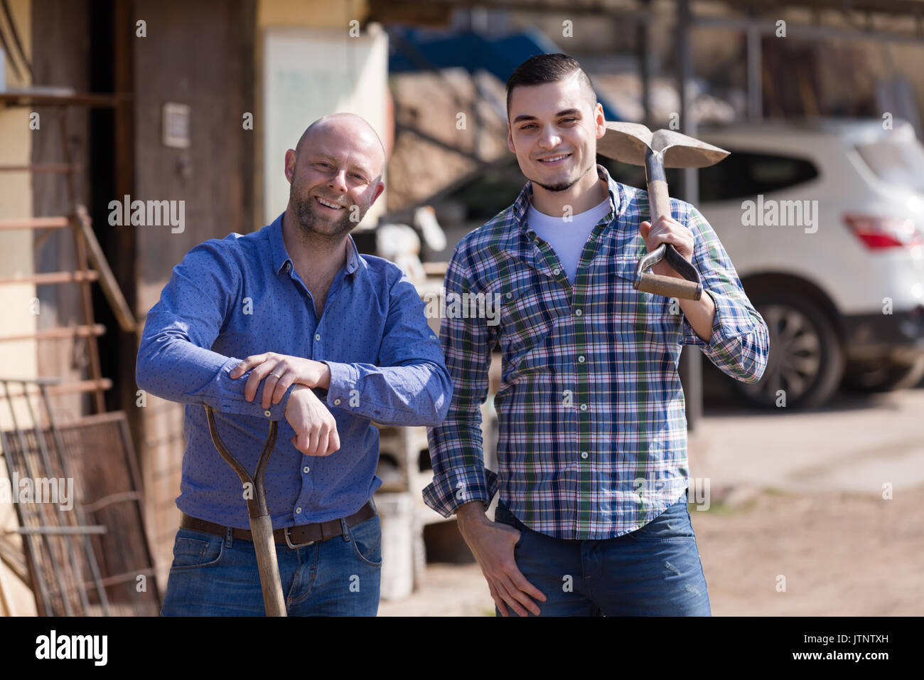 Two male farmers standing with spades at farmyard Stock Photo - Alamy