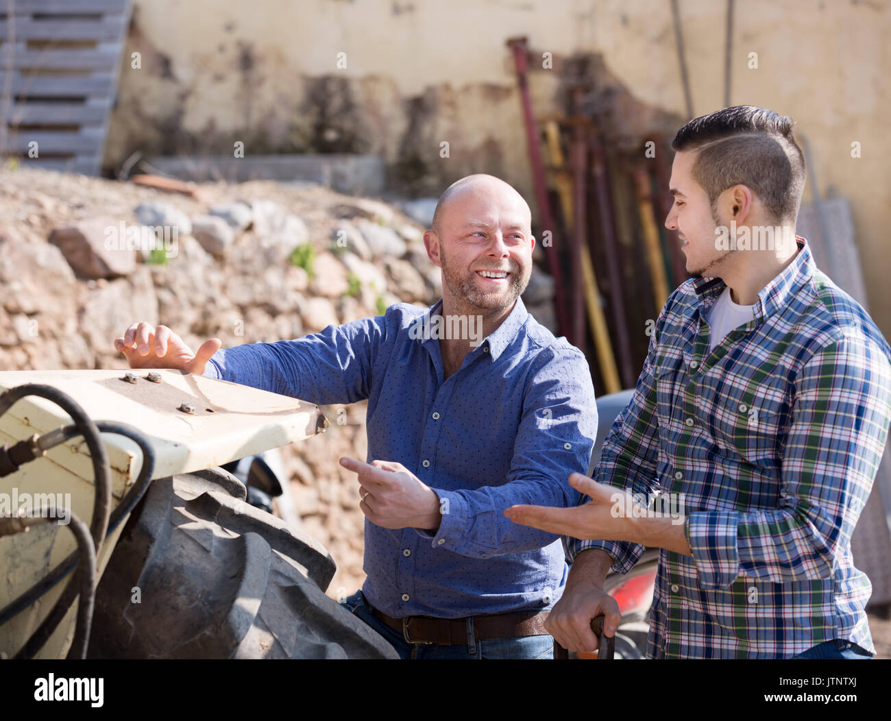 Two farmers talking near the agricultural machinery in shed Stock Photo ...