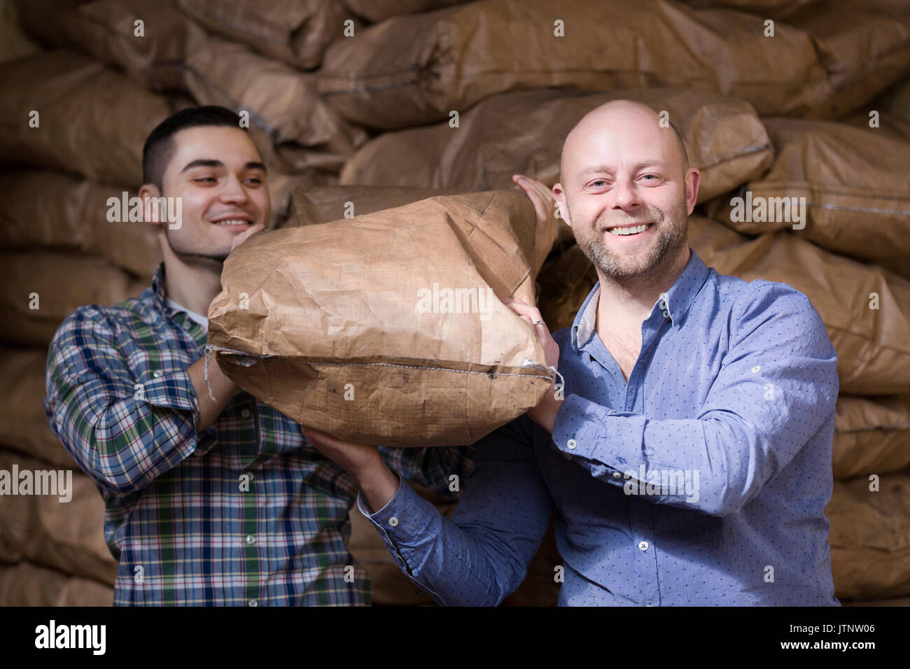 Strong workmen unloading shed with coal bags Stock Photo - Alamy