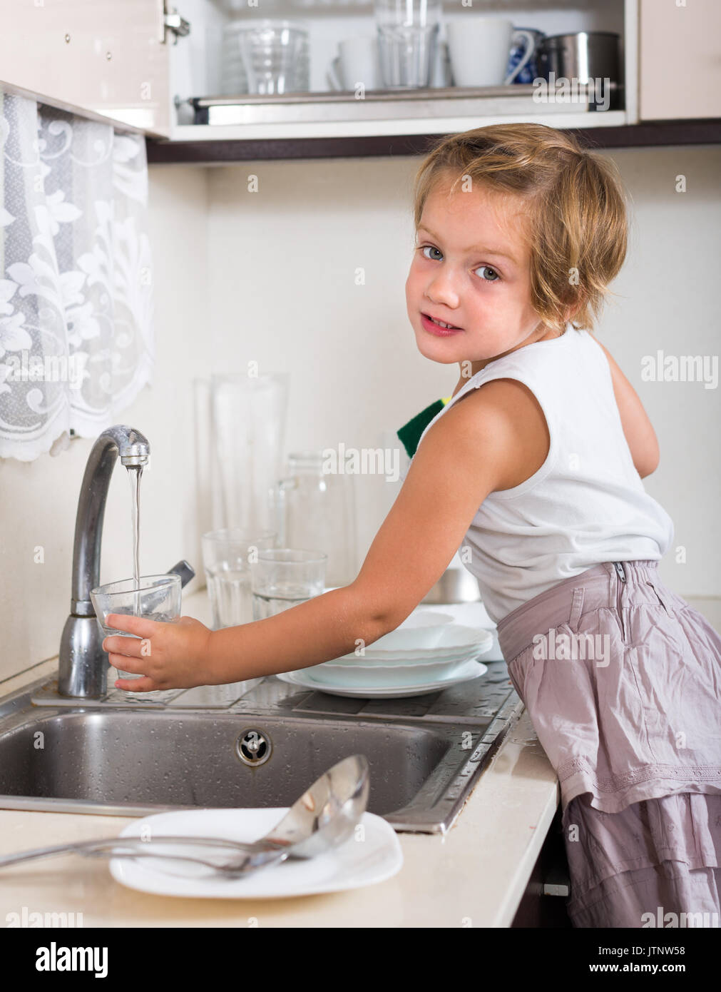 Happy cute little girl washing dishes at domestic kitchen Stock Photo ...