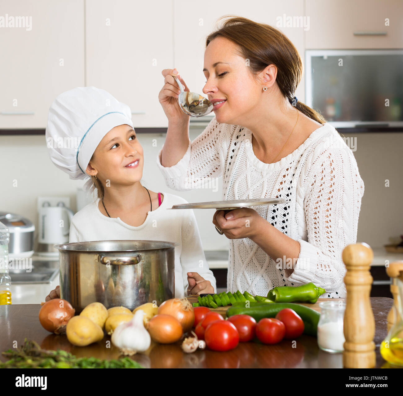 Happy smiling mother and her cheerful daughter preparing soup at ...