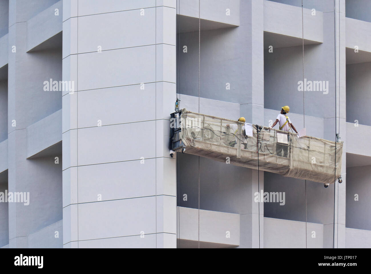 Construction workers in lift hanging from the building Stock Photo - Alamy
