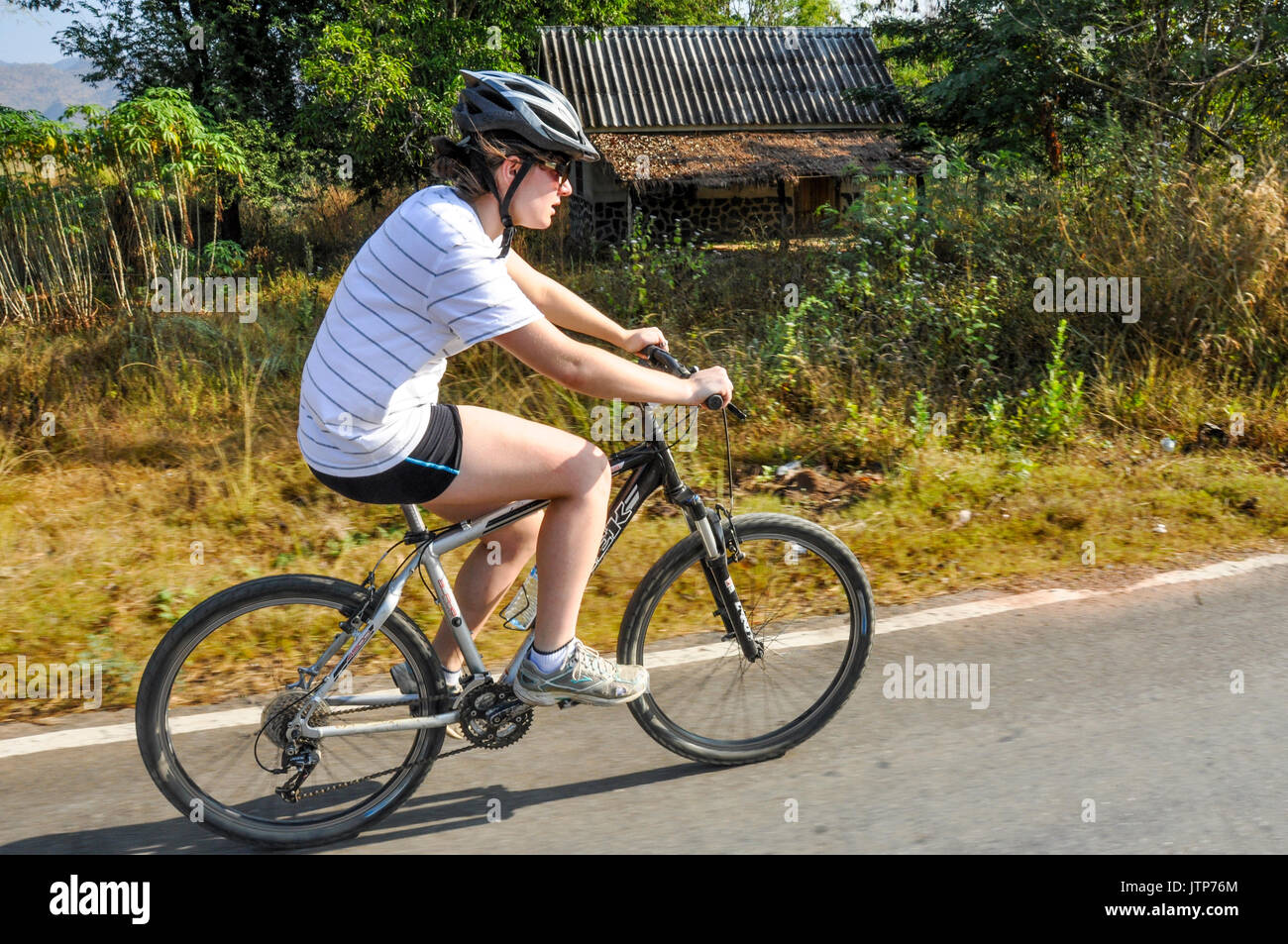 A female touring cyclist cycling on a country road in the countryside ...