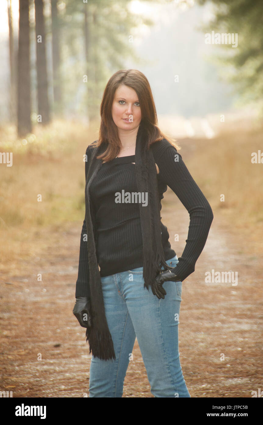 Pretty girl in a forest wearing jeans and a black top Stock Photo - Alamy