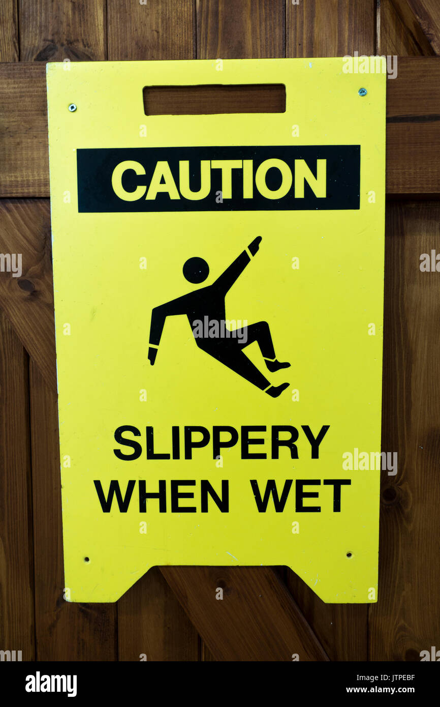 'Caution Slippery when wet' warning sign on a wooden door inside a UK ...