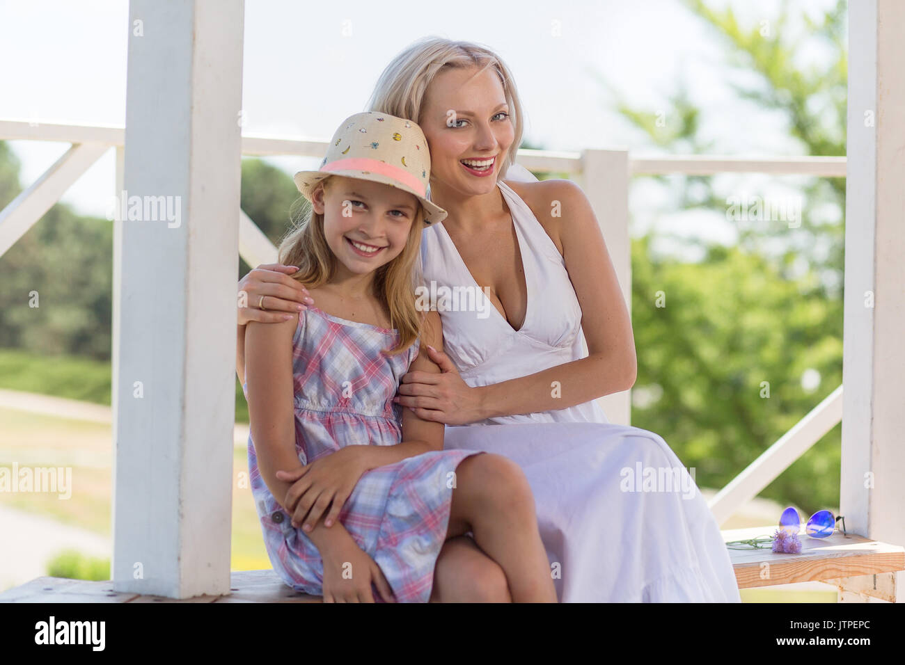 Happy mother and daughter sitting on bench at summer house Stock Photo ...