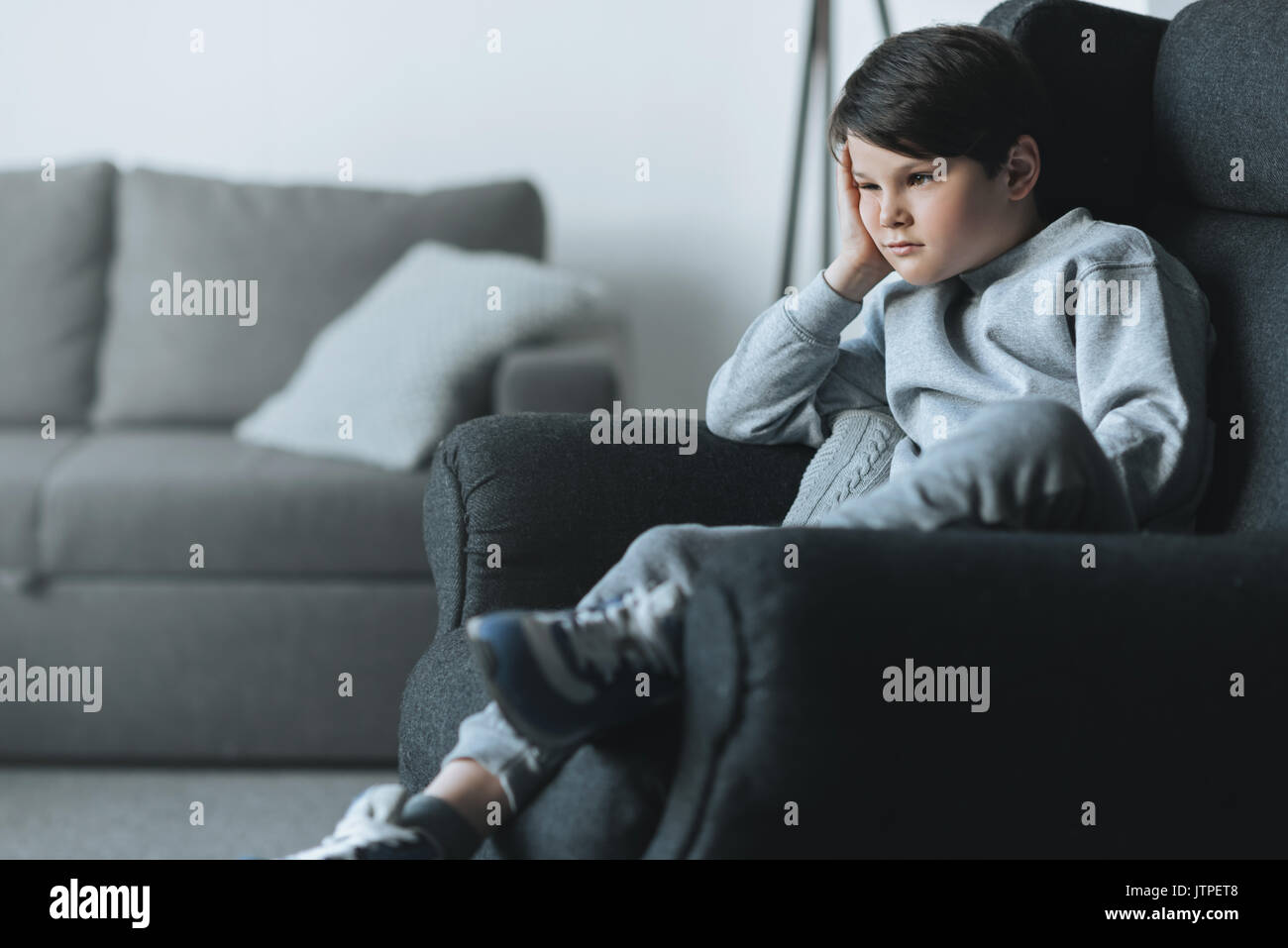 pensive little kid boy sitting on sofa at home Stock Photo - Alamy