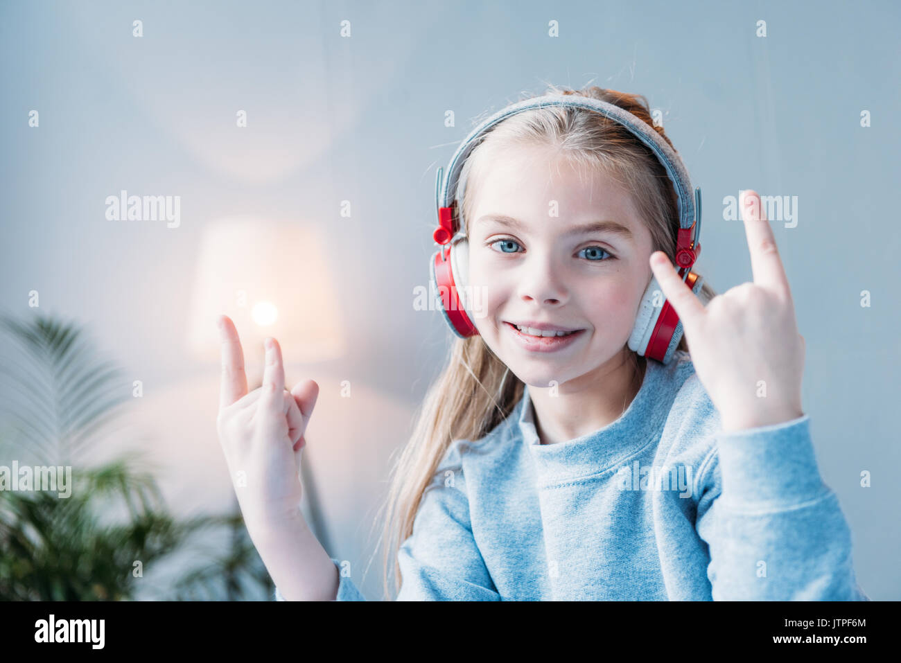 portrait of smiling little girl in headphones showing rock signs Stock ...