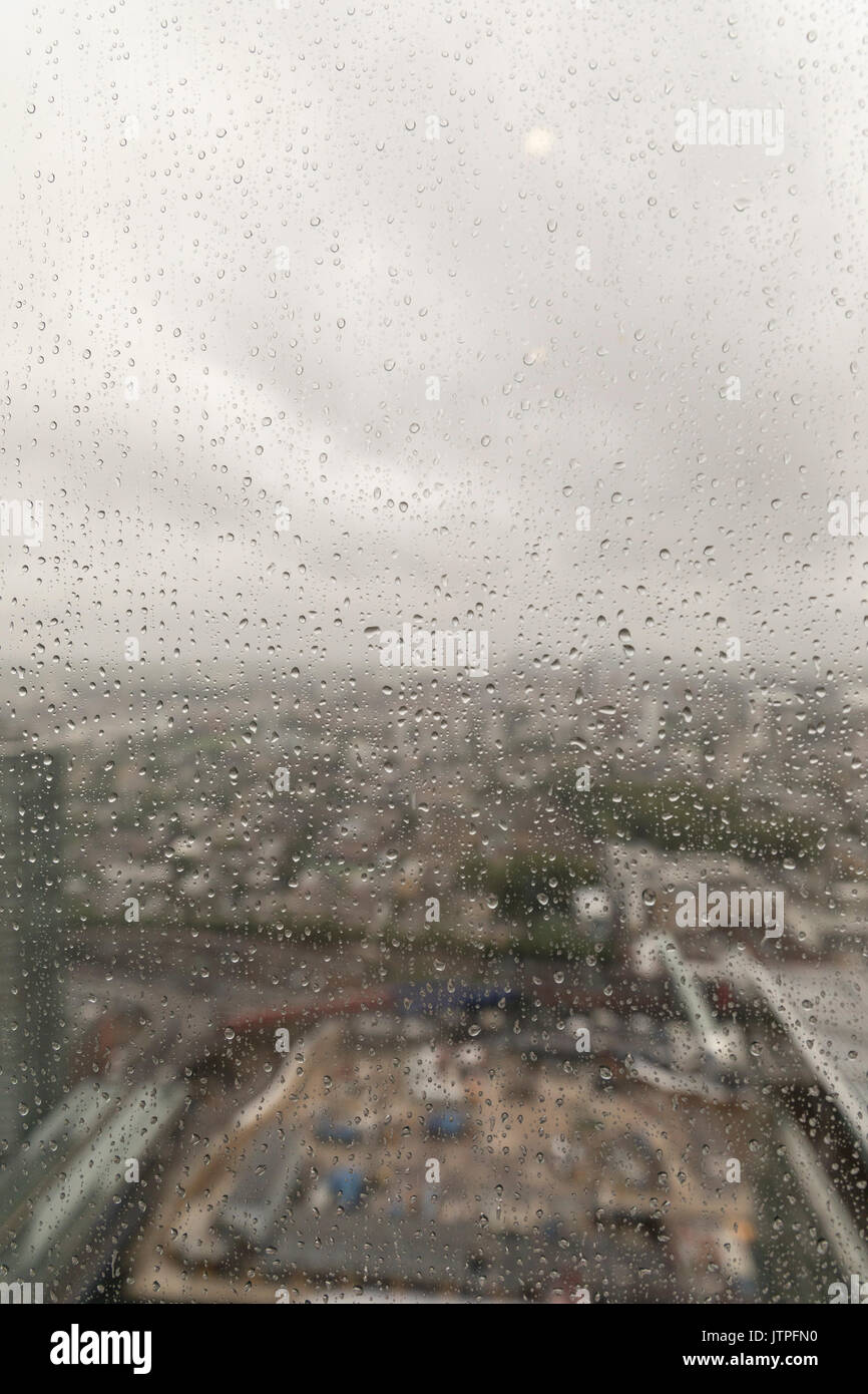 Grey Rainy day in London view through high rise window with rain drops ...