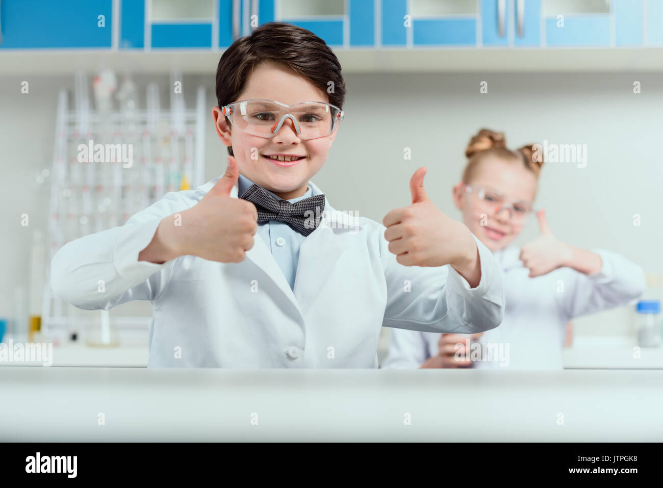 schoolchildren showing thumbs up in chemical lab, scientists kids team ...