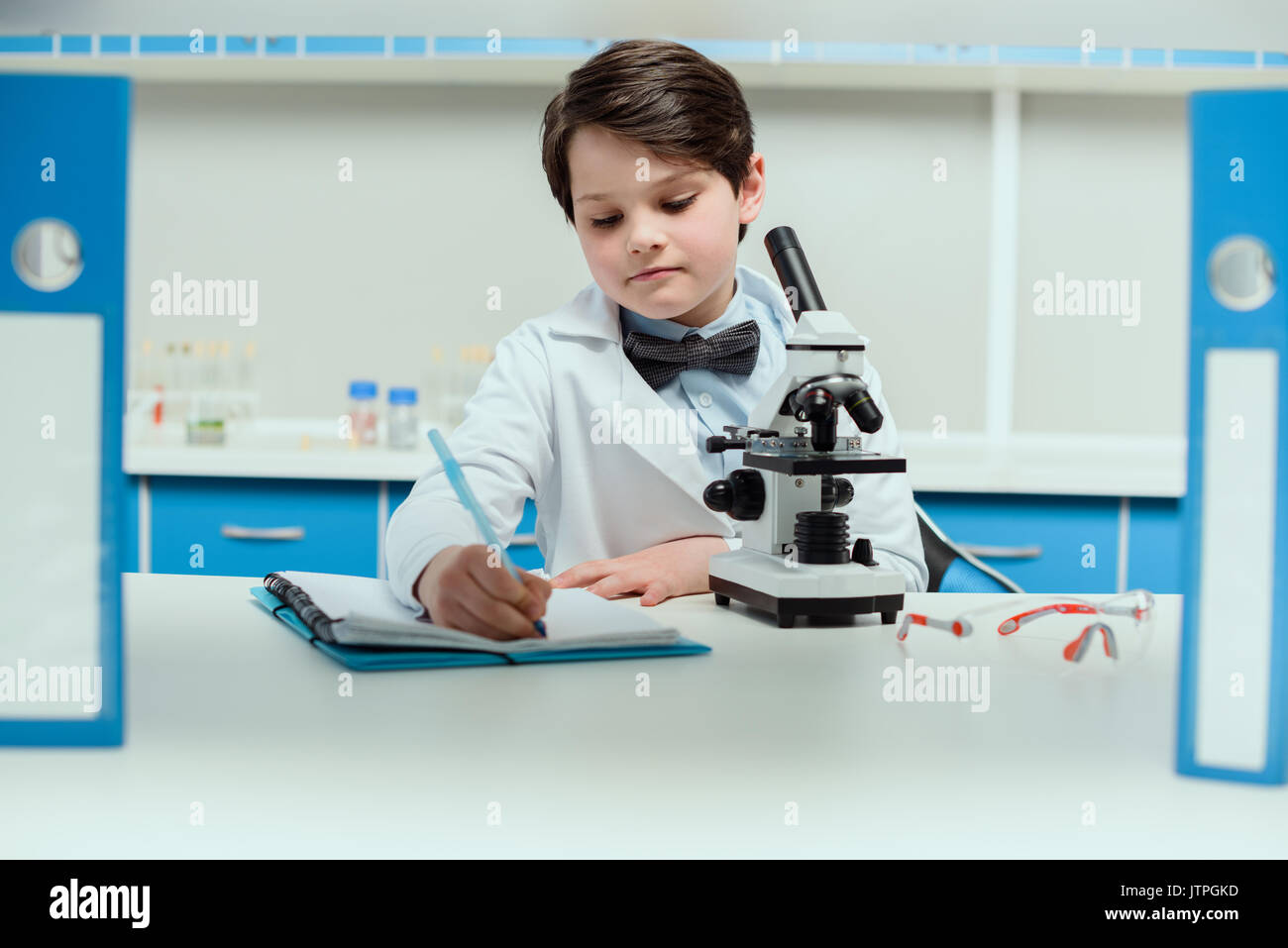 schoolboy with microscope and copybook in science laboratory, science lab kids concept Stock ...