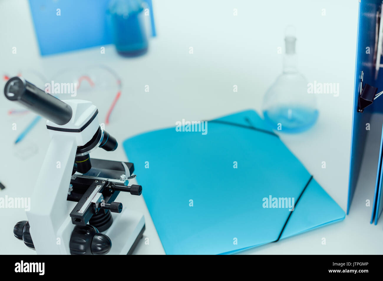 folder, tube with blue reagent and microscope on tabletop in chemical ...