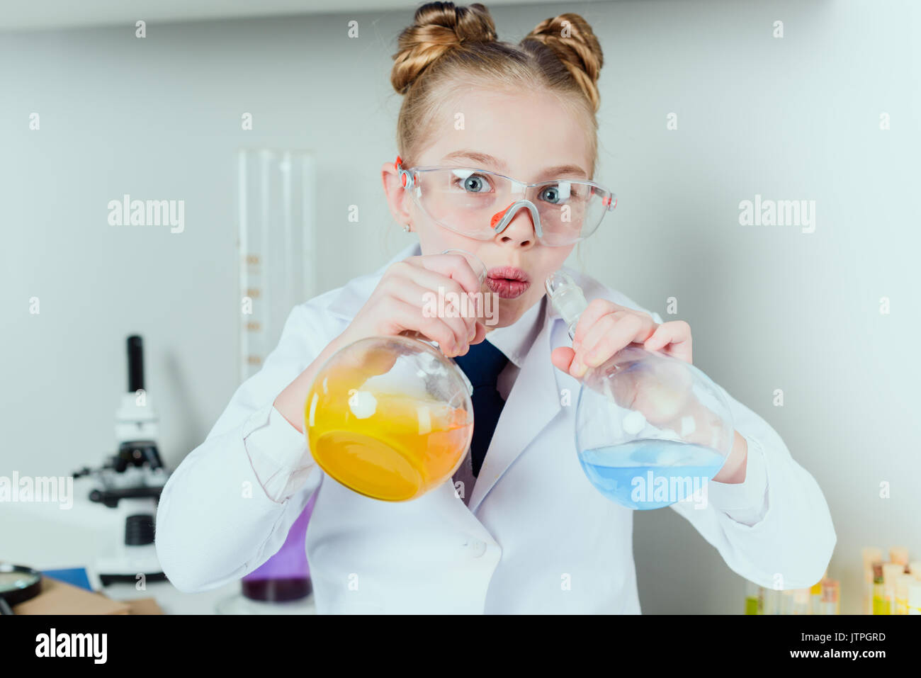 Little scientist in lab coat and protective eyeglasses making ...