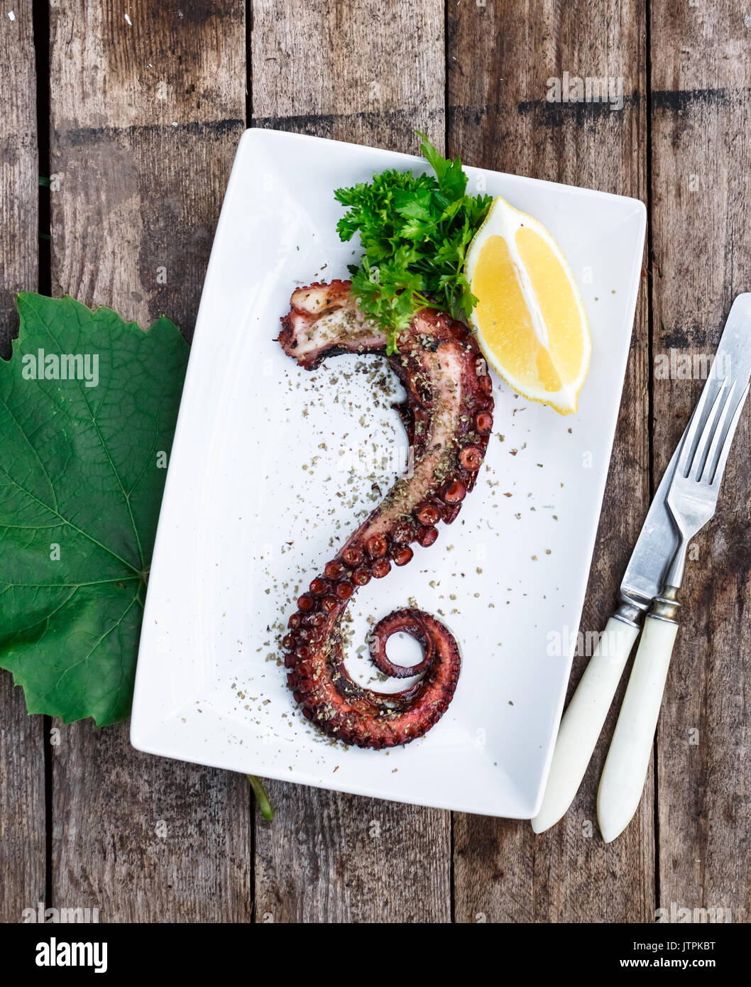 Served Octopus Tentacle on White plate with lemon and oregano Stock ...