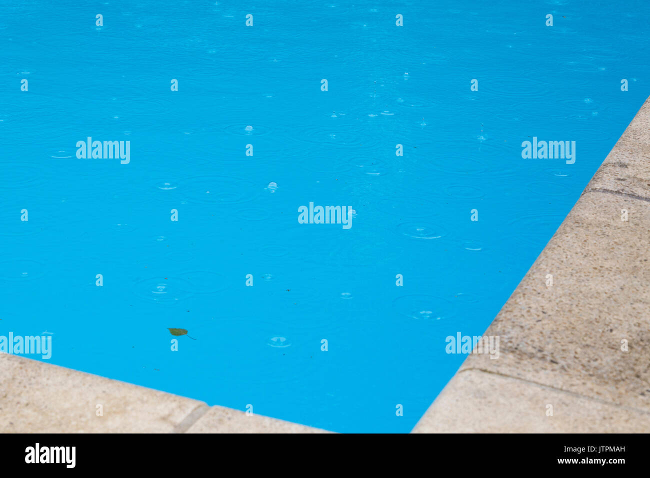 Raindrops Falling into an outdoor swimming pool with blue water Stock ...