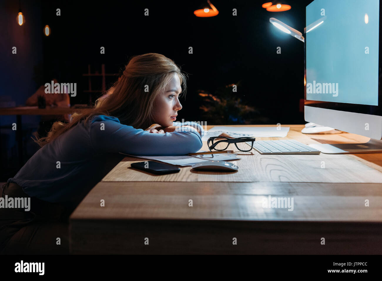 side view of exhausted businesswoman looking at computer screen at ...