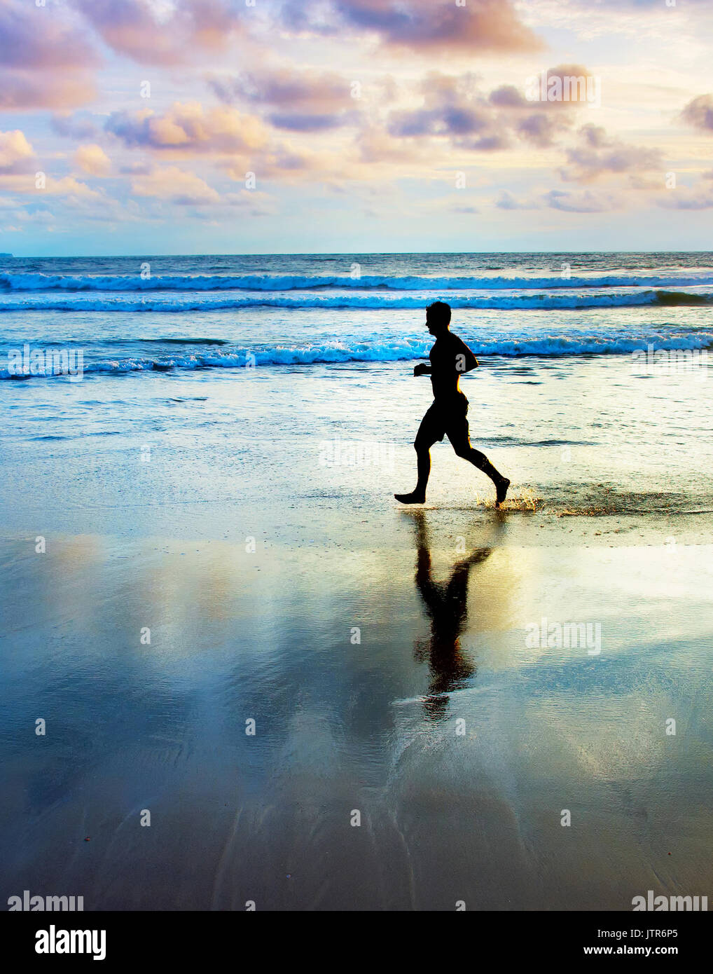 Man running on the tropical ocean beach at sunset Stock Photo - Alamy
