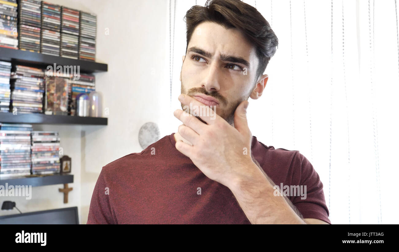 Confused or doubtful young man scratching his chin Stock Photo - Alamy