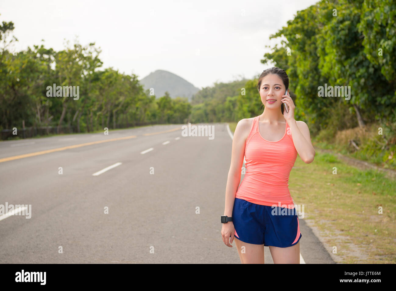 woman runner standing on road to calling for family through mobile ...