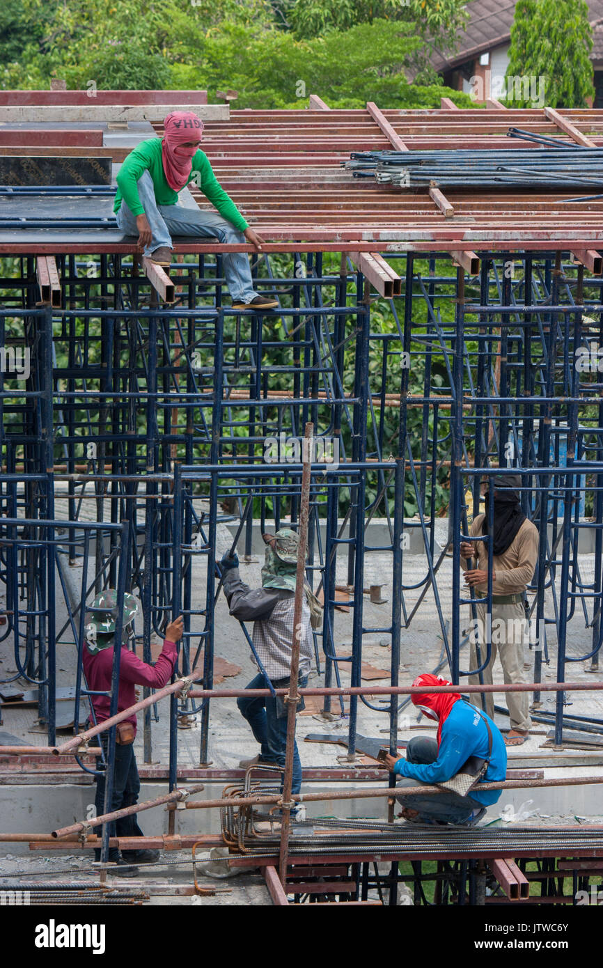 Thai construction workers build a scaffolding in a precarious position ...