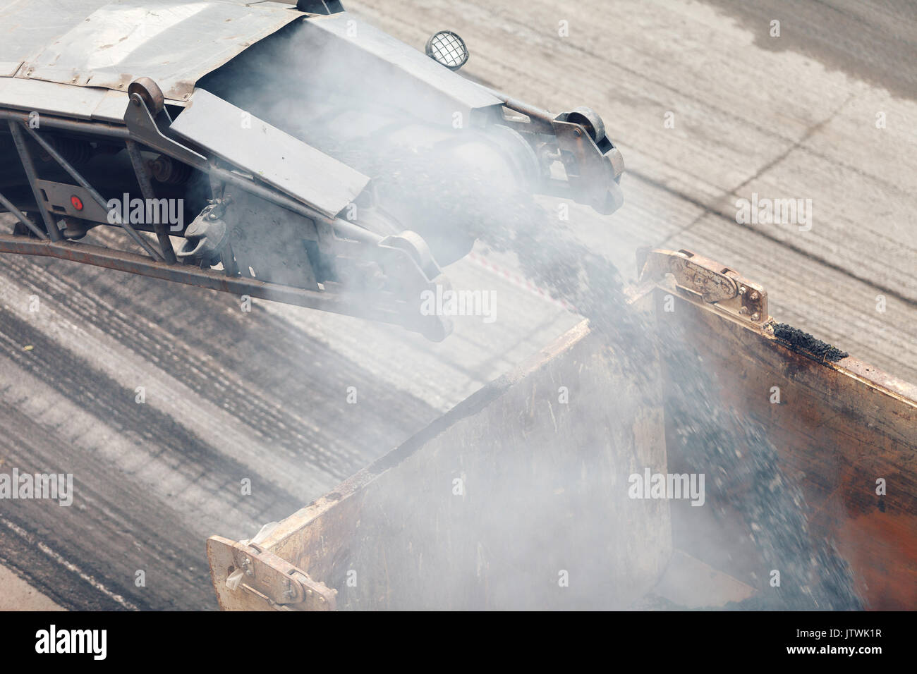 Road works. Asphalt removing machine loading powdered asphalt on the ...