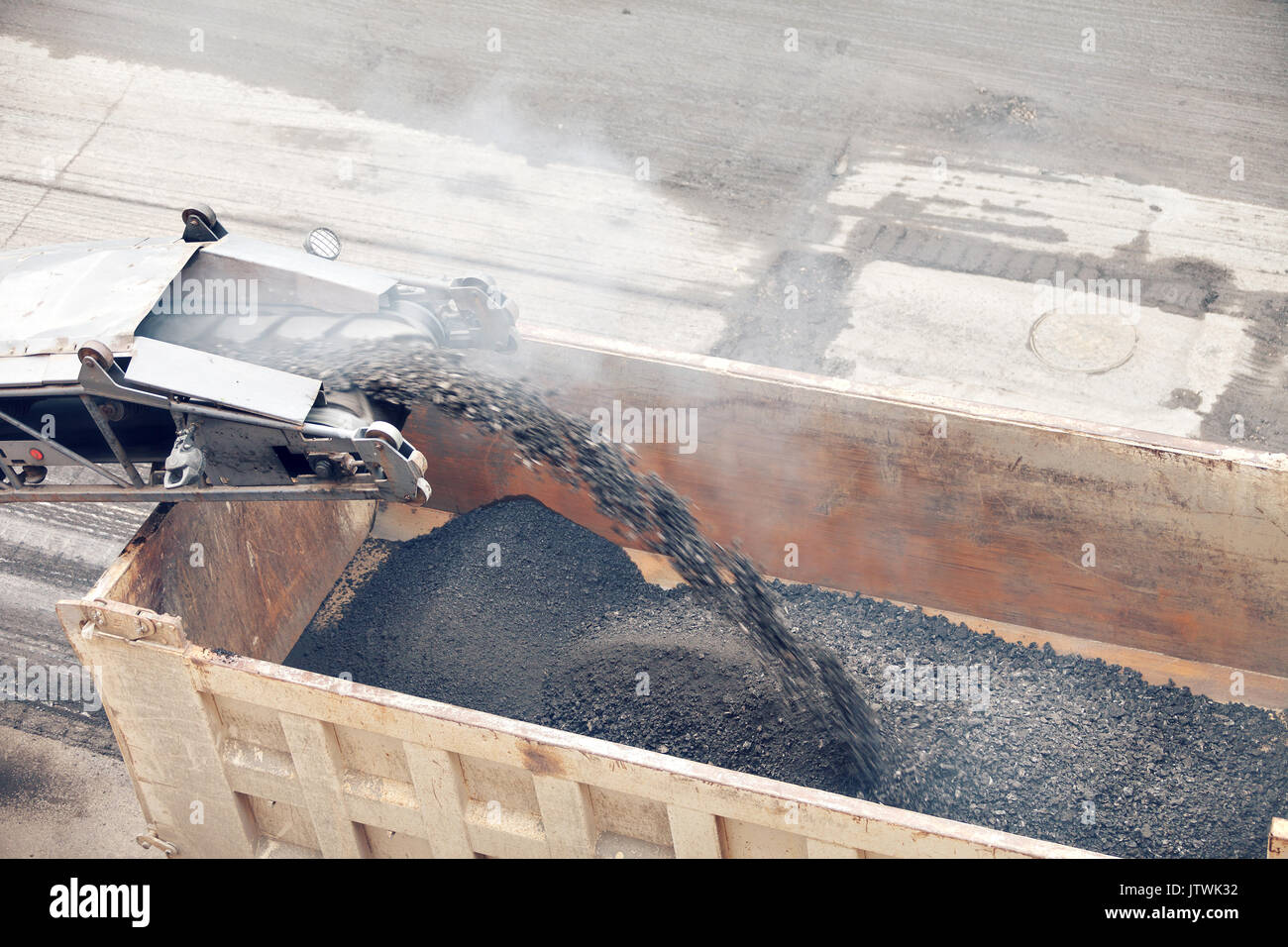Road works. Asphalt removing machine loading powdered asphalt on the ...