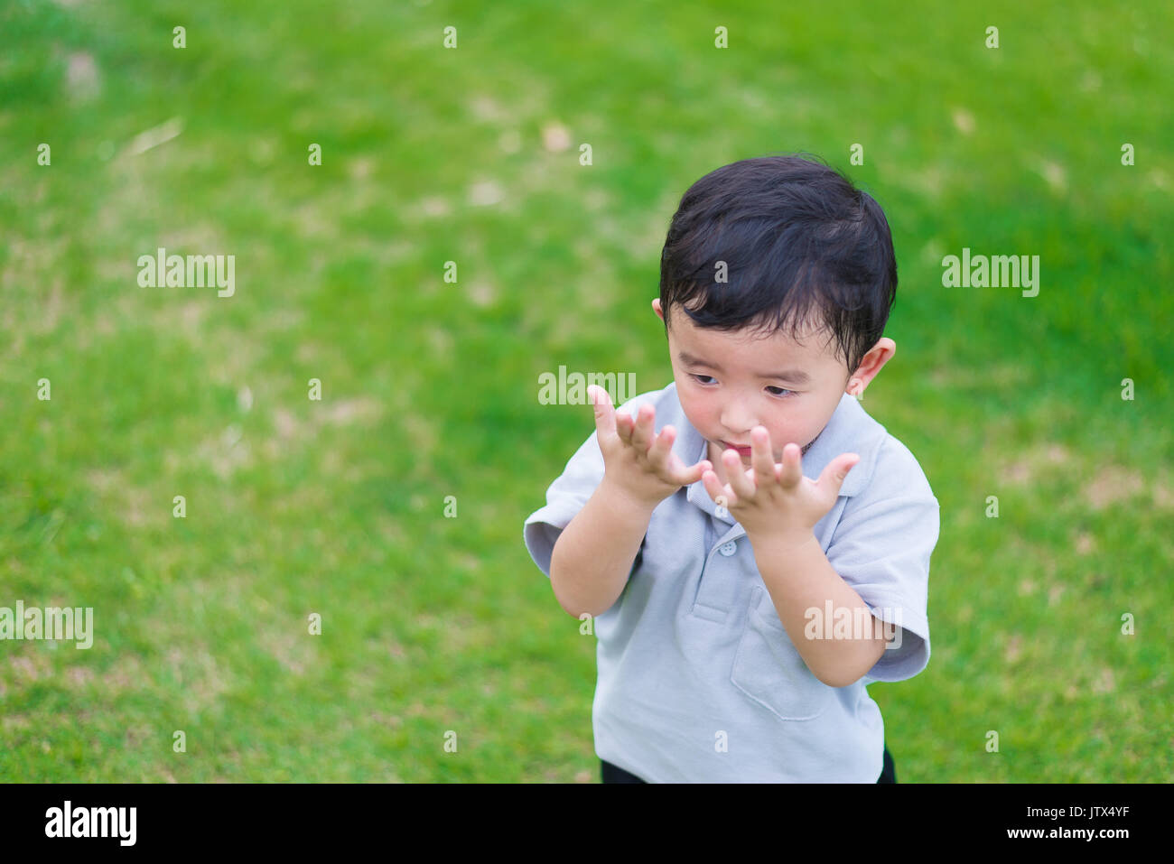 Little Asian kid at the playground under the sunlight in summer ...